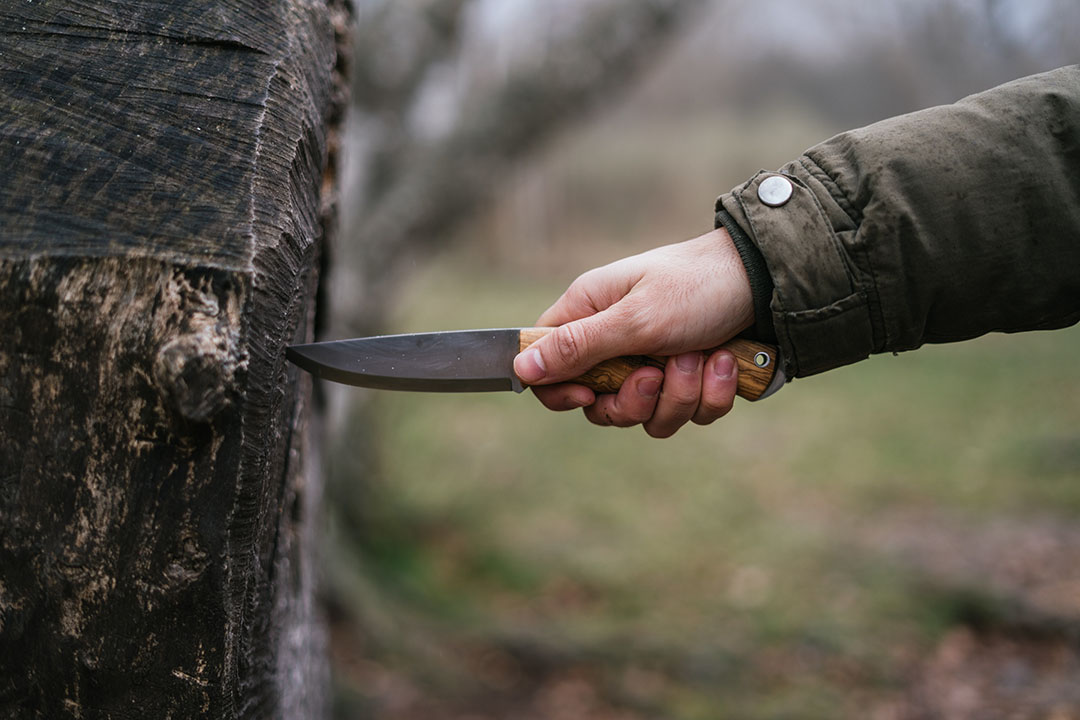 Closeup shot of a hand pulling a knifee stuck in wood | Knifewarehouse